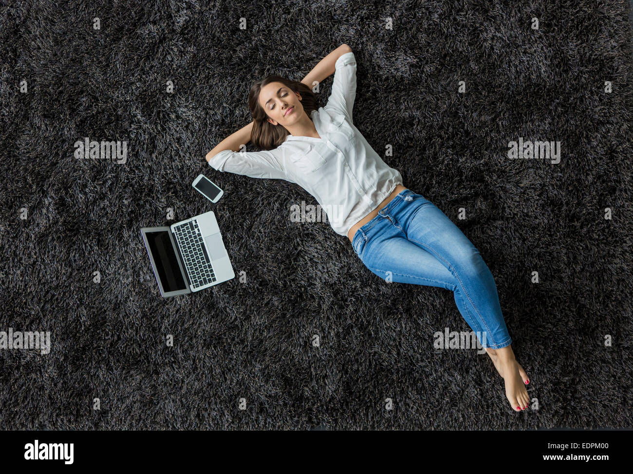 Young woman laying on the carpet Stock Photo - Alamy