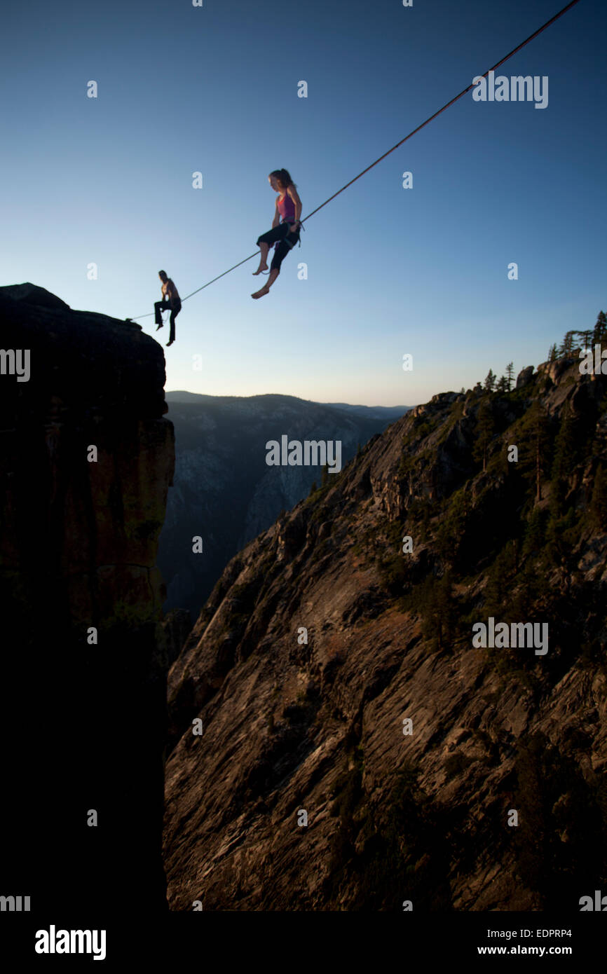 Female highliners simultaneously sitting on a highline above the ...