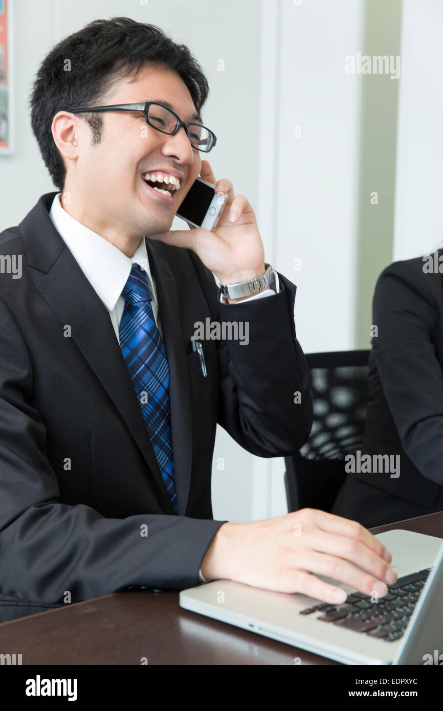 Businessman Talking on Mobile Phone and Using Computer Stock Photo - Alamy