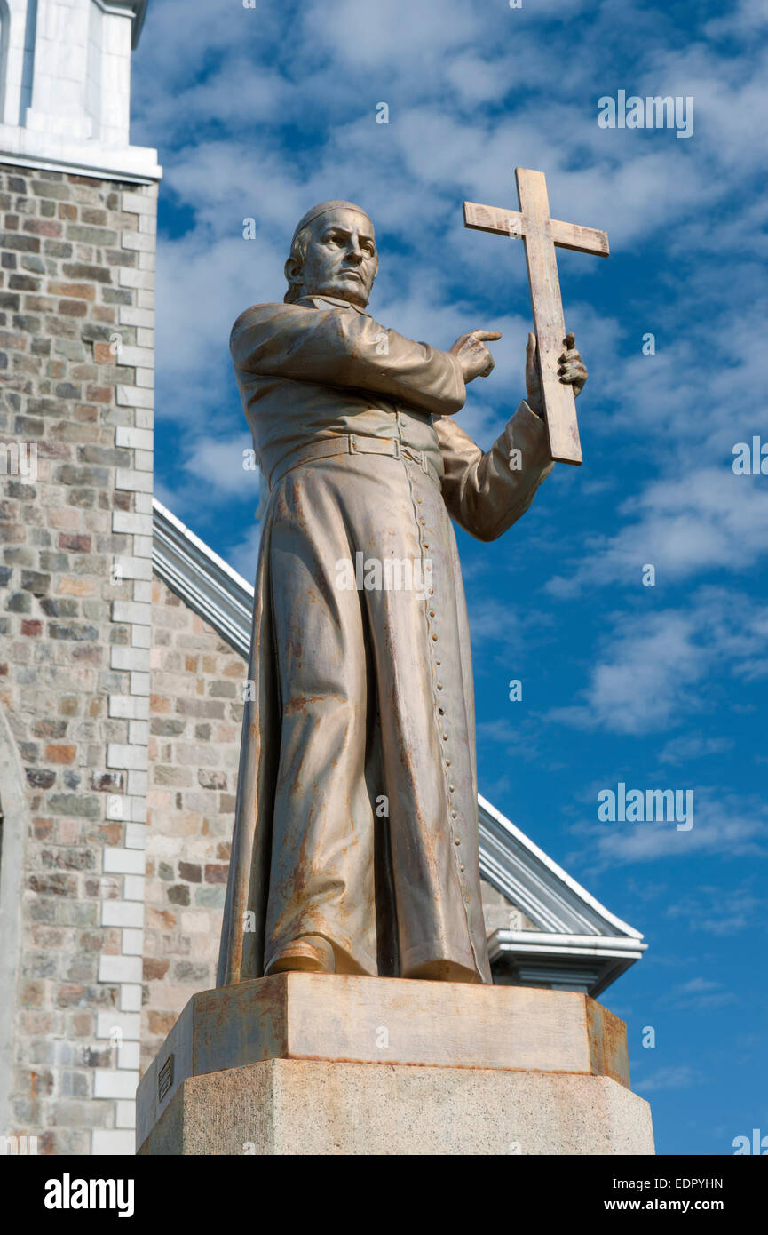 Statue of a priest standing on the grounds of the Catholic church of ...