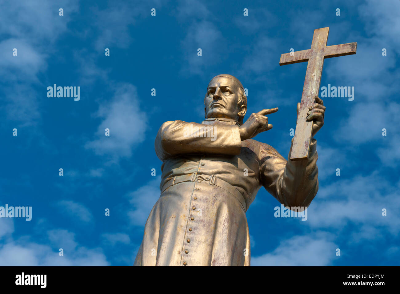 Statue of a priest standing on the grounds of the Catholic church of ...