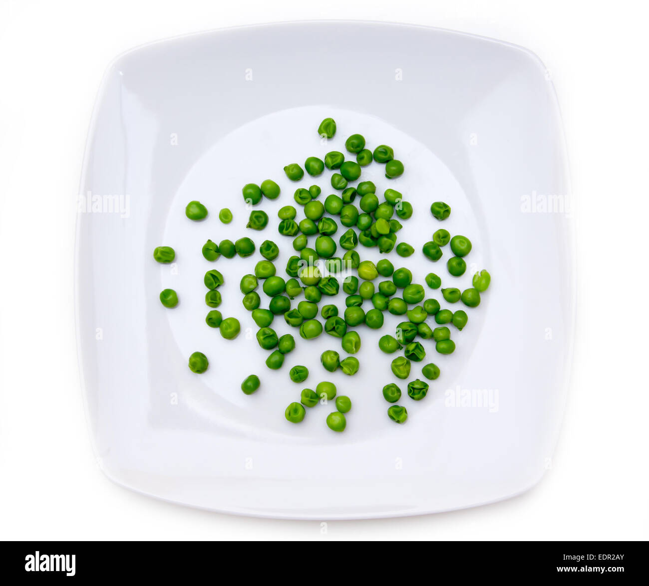 Plate with cooked green peas on a white background seen from above ...
