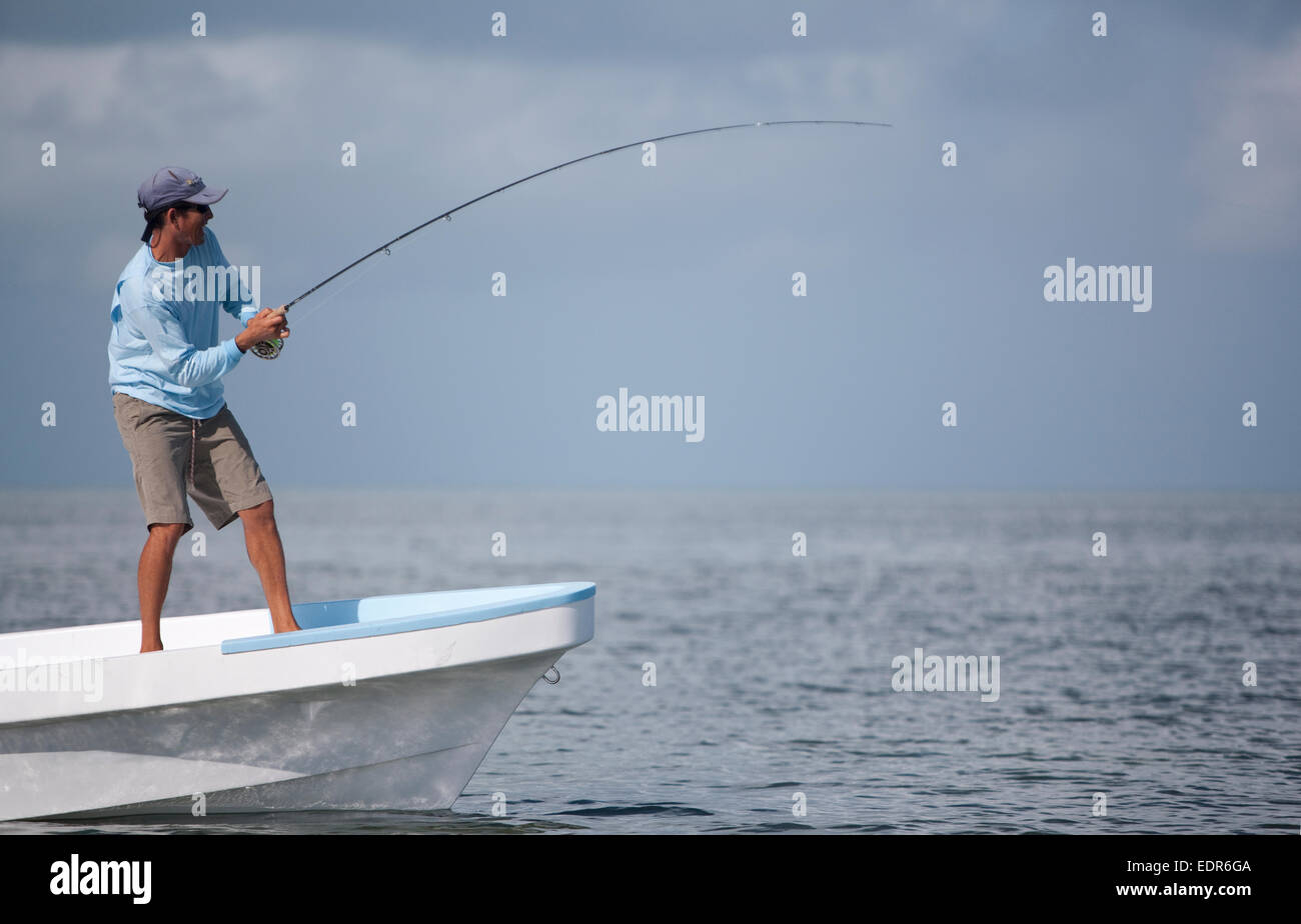 fisherman stands on bow of boat while reeling in fly rod Stock Photo ...
