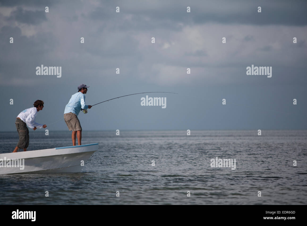 fisherman stands on bow of boat while reeling in fly rod Stock Photo ...