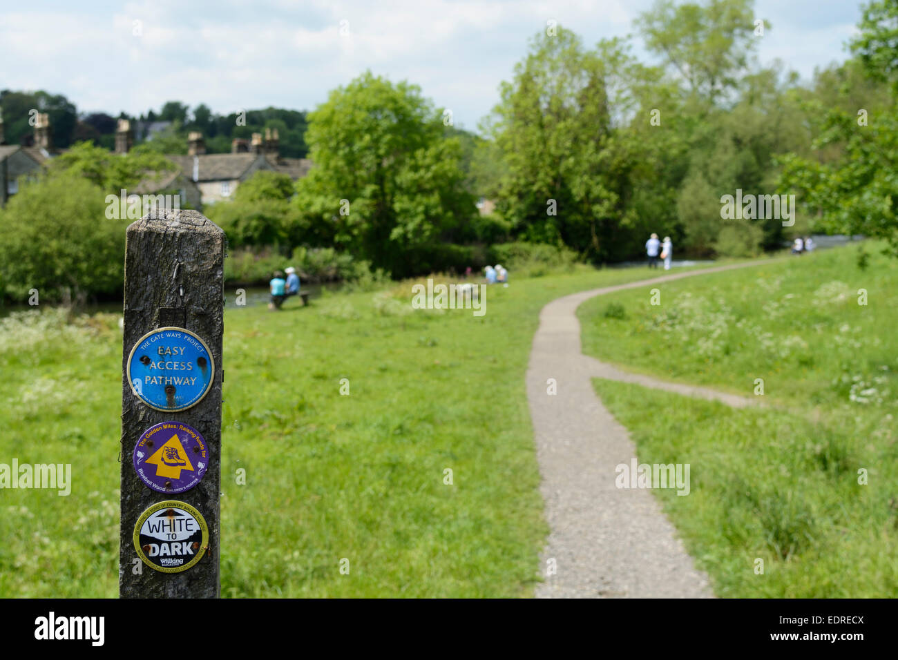 Wooden signpost with directions on with people in distance background ...