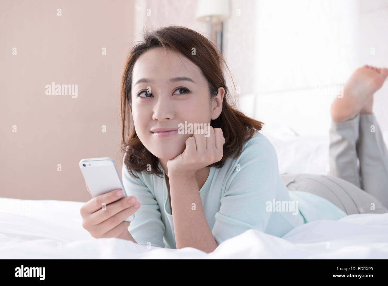 Woman lying on hotel bed with phone hi-res stock photography and images ...
