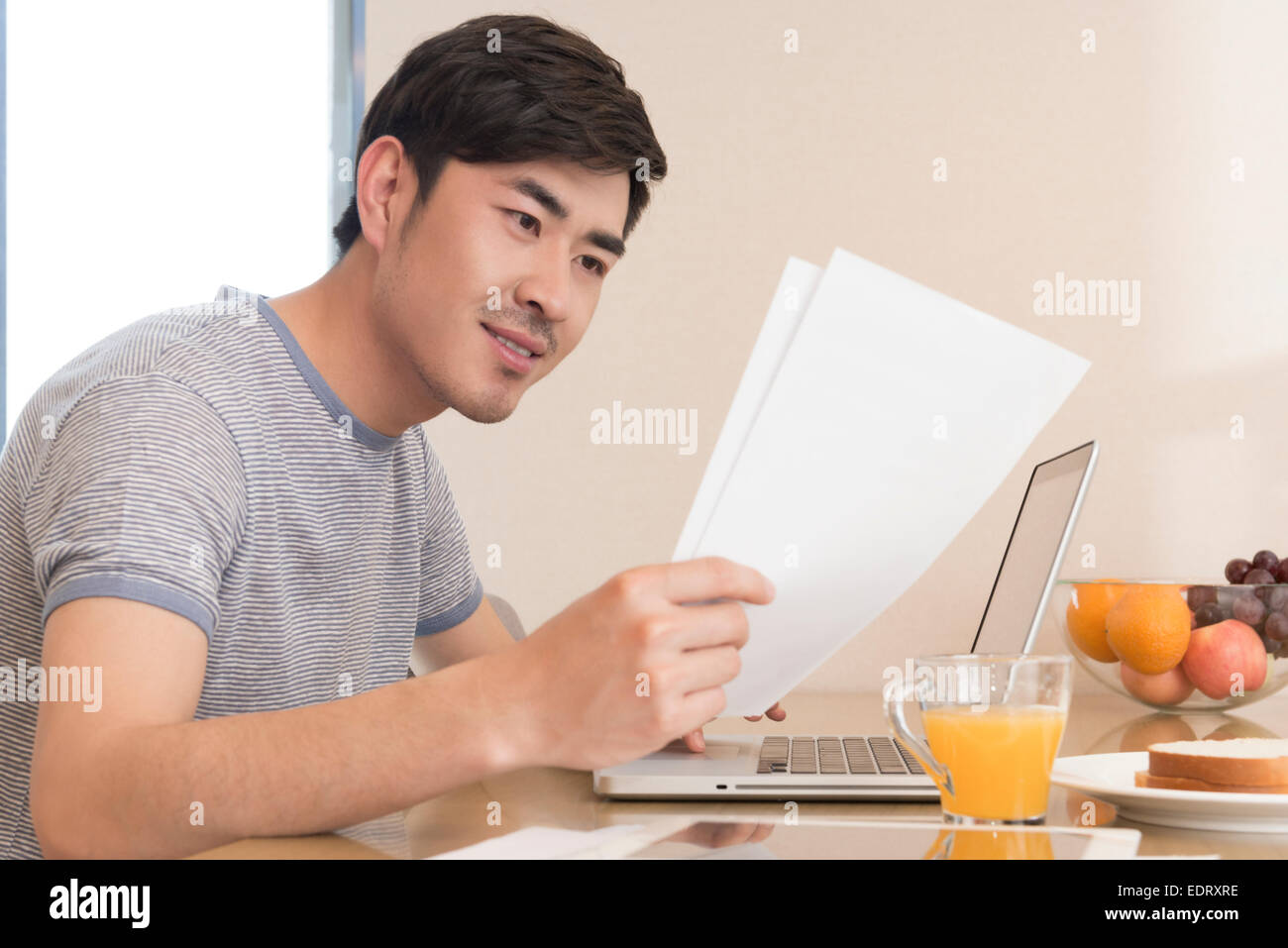 Young man looking at paperwork at breakfast Stock Photo - Alamy