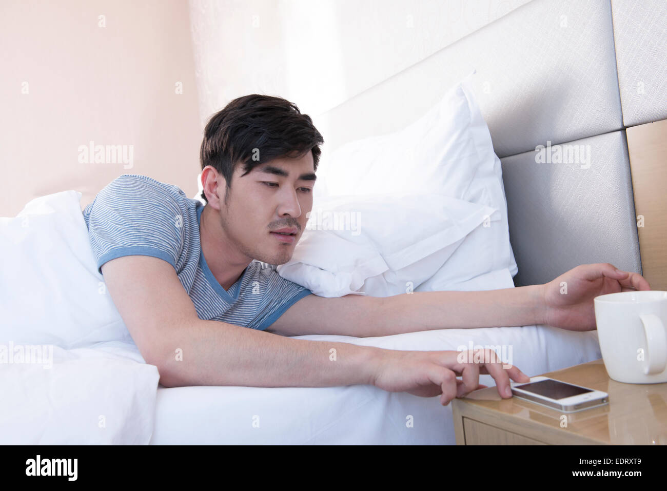 Young man checking mobile phone in bed Stock Photo - Alamy