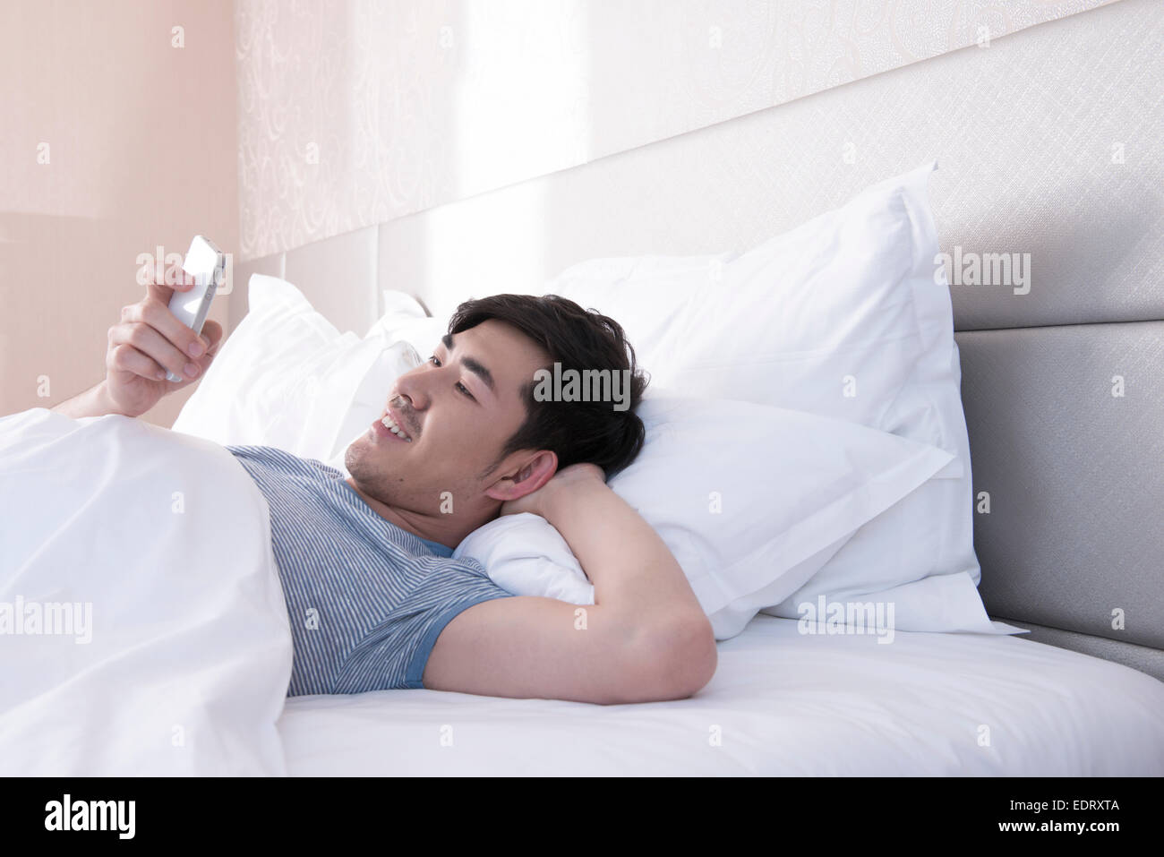 Young man checking mobile phone in bed Stock Photo - Alamy
