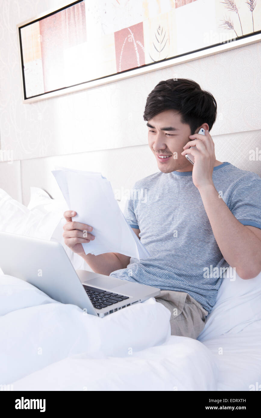 Young man working in bed Stock Photo - Alamy