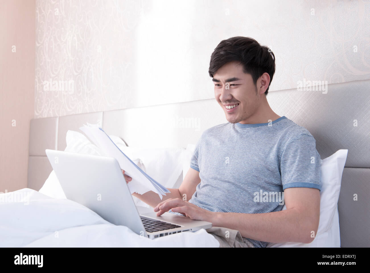 Young man looking at paperwork in bed Stock Photo - Alamy