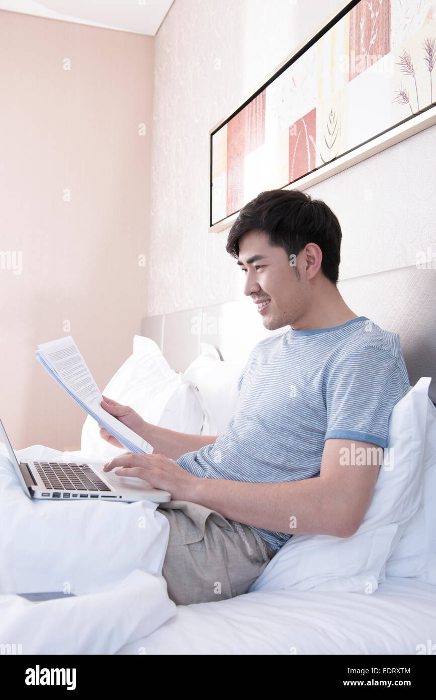 Young man working in bed Stock Photo - Alamy