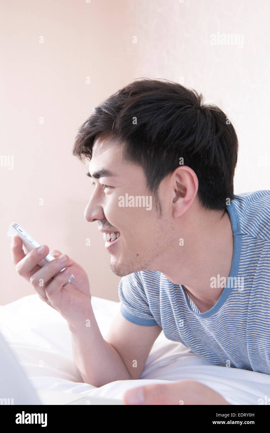 Young man using smart phone in bed Stock Photo - Alamy