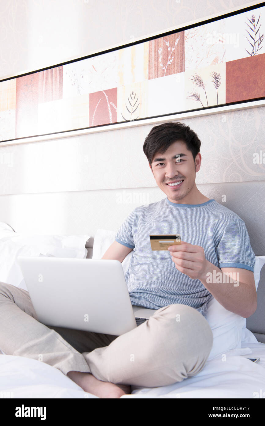 Young man shopping online in bed Stock Photo - Alamy