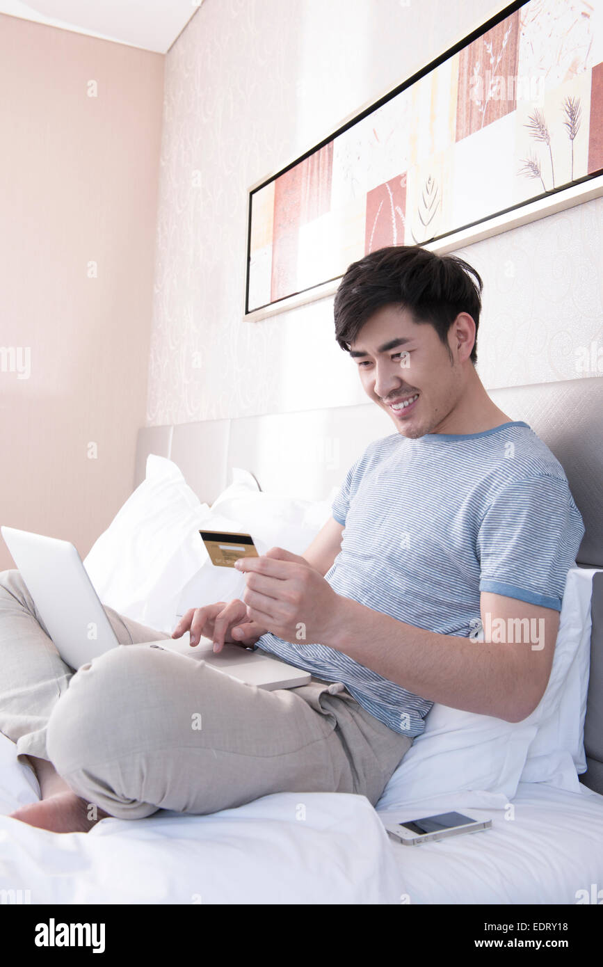 Young man shopping online in bed Stock Photo - Alamy
