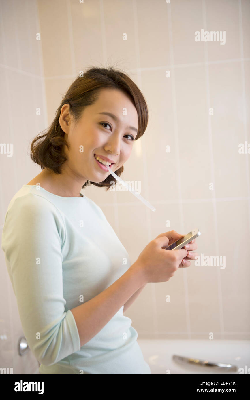 Young woman texting in bathroom Stock Photo - Alamy