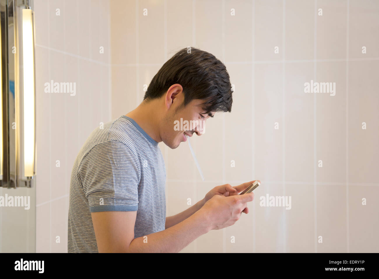 Young man texting in bathroom Stock Photo - Alamy