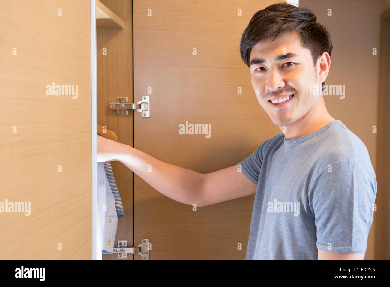 Young man taking clothes from closet Stock Photo - Alamy