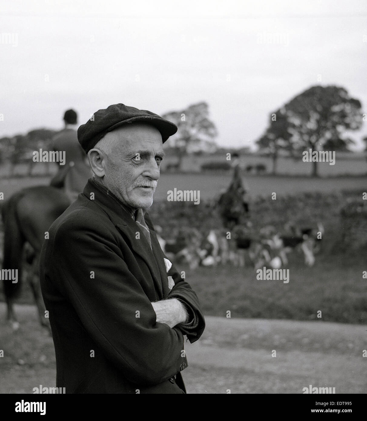 1950s historical picture showing a man in cloth cap following a local ...