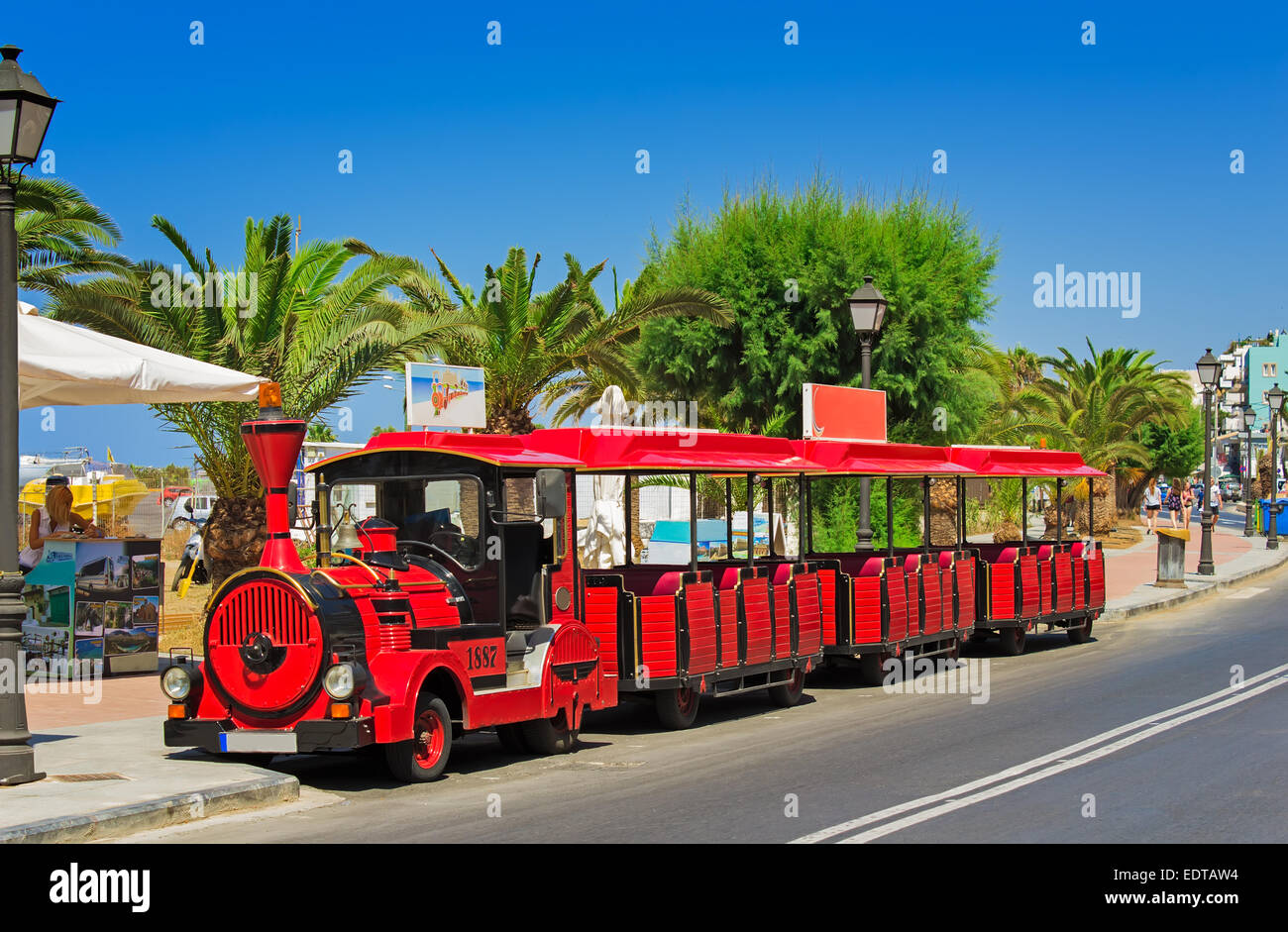 Bright red car in the style of an old steam train with open cars in the ...