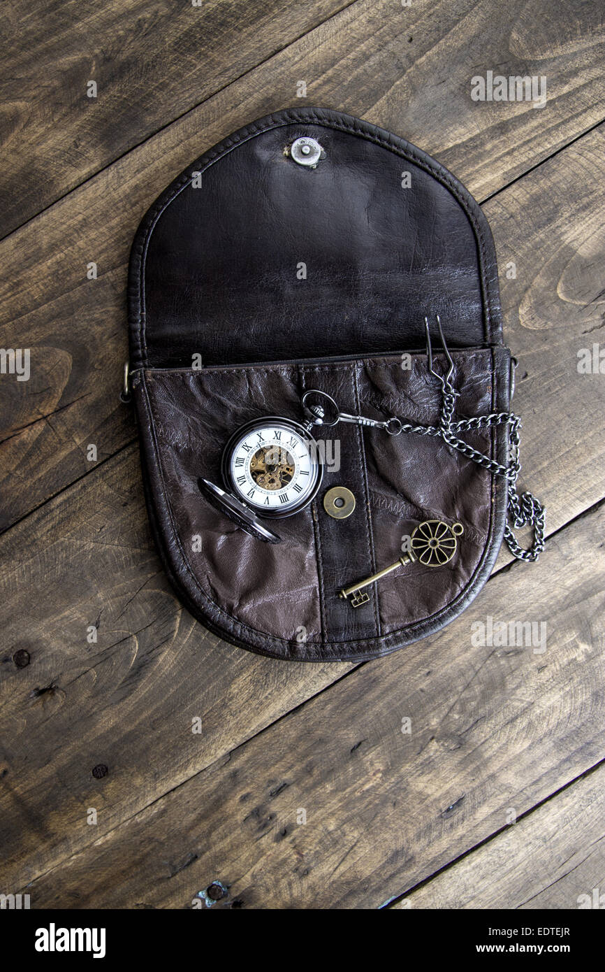 Vintage pocket watch, old bag and a brass key on a vintage surface ...