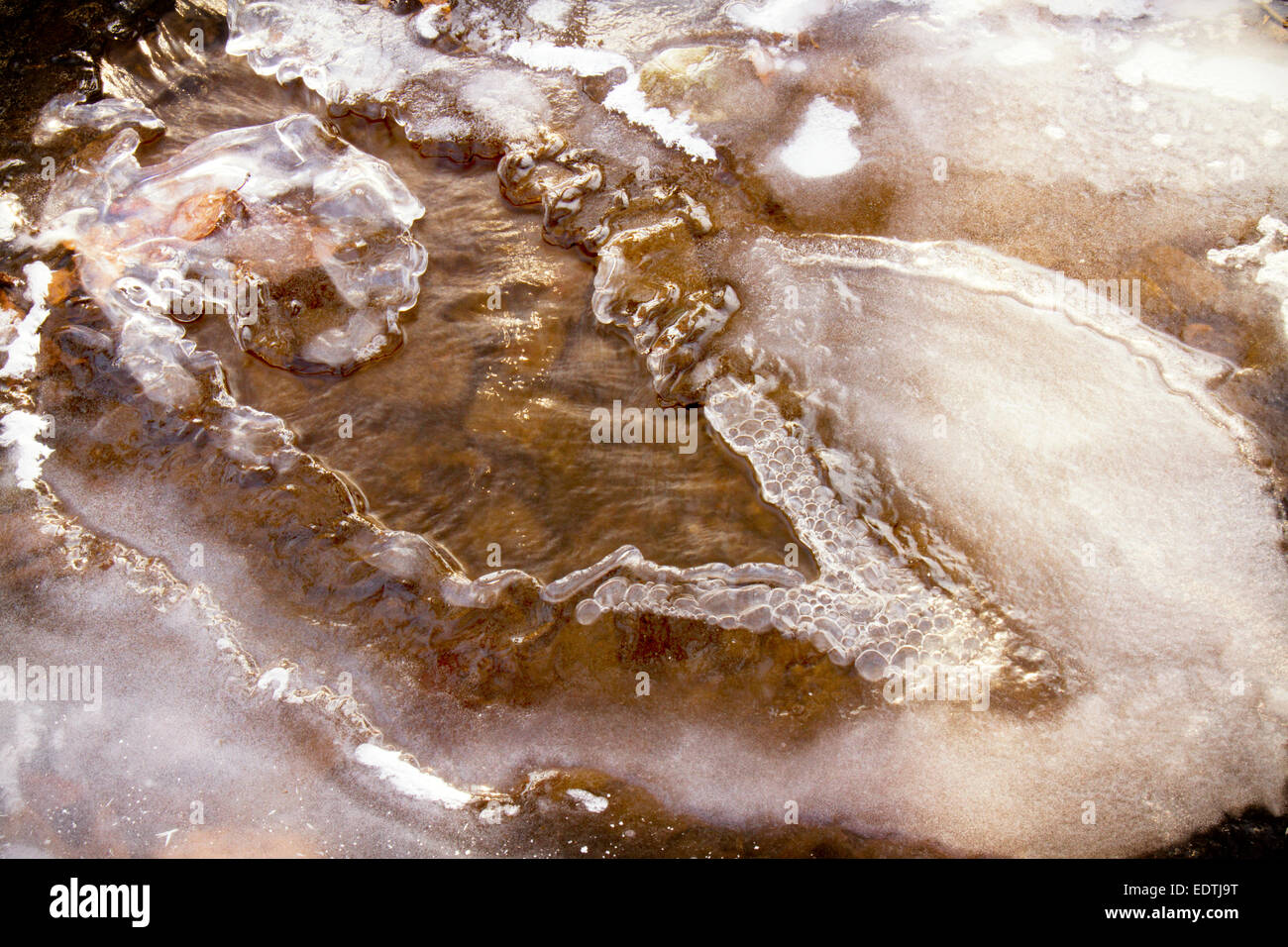 Ice partially covering freezing running stream in winter with snow ...