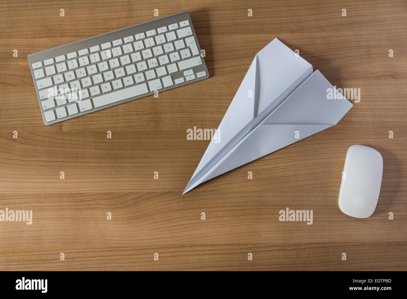 Paper Airplane on a wooden office desk with modern keyboard and mouse ...