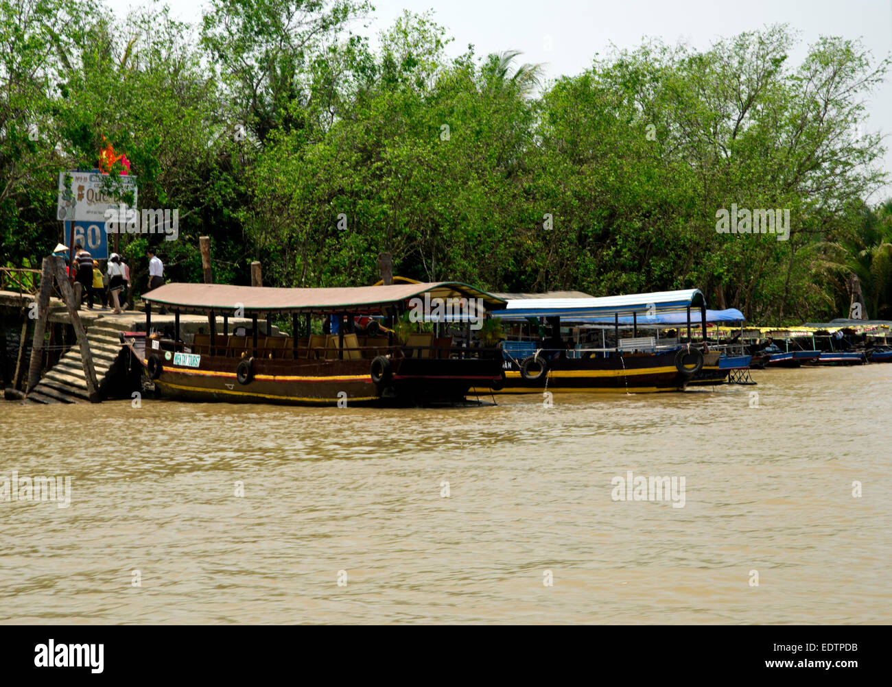 Tour boats tied up at Ben Tre Island, Mekong delta. Passengers get off ...