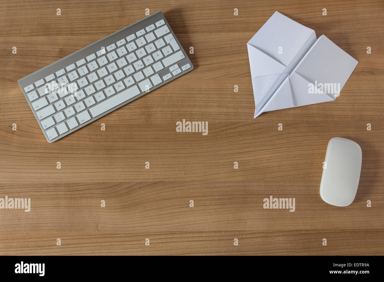 Paper Airplane on a wooden office desk with modern keyboard and mouse ...