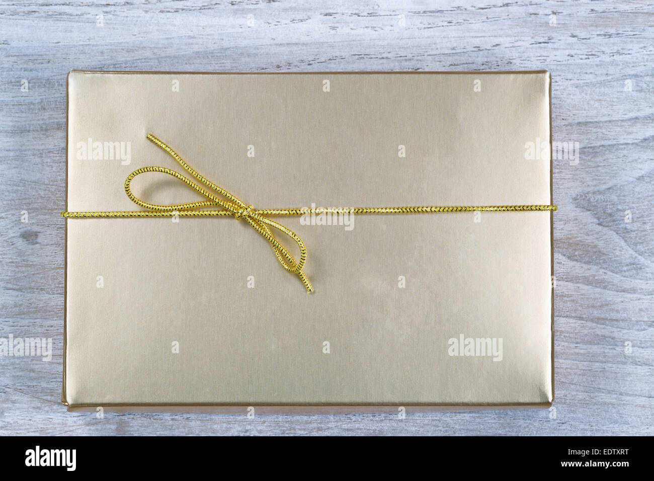 Close up horizontal image of a golden color gift box on rustic white ...