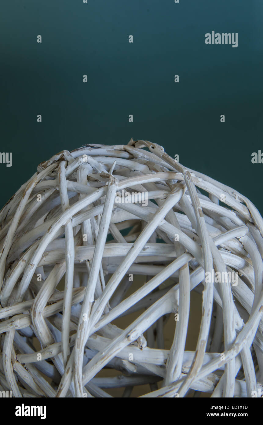 A worn white wicker ball against a teal blue wall Stock Photo - Alamy
