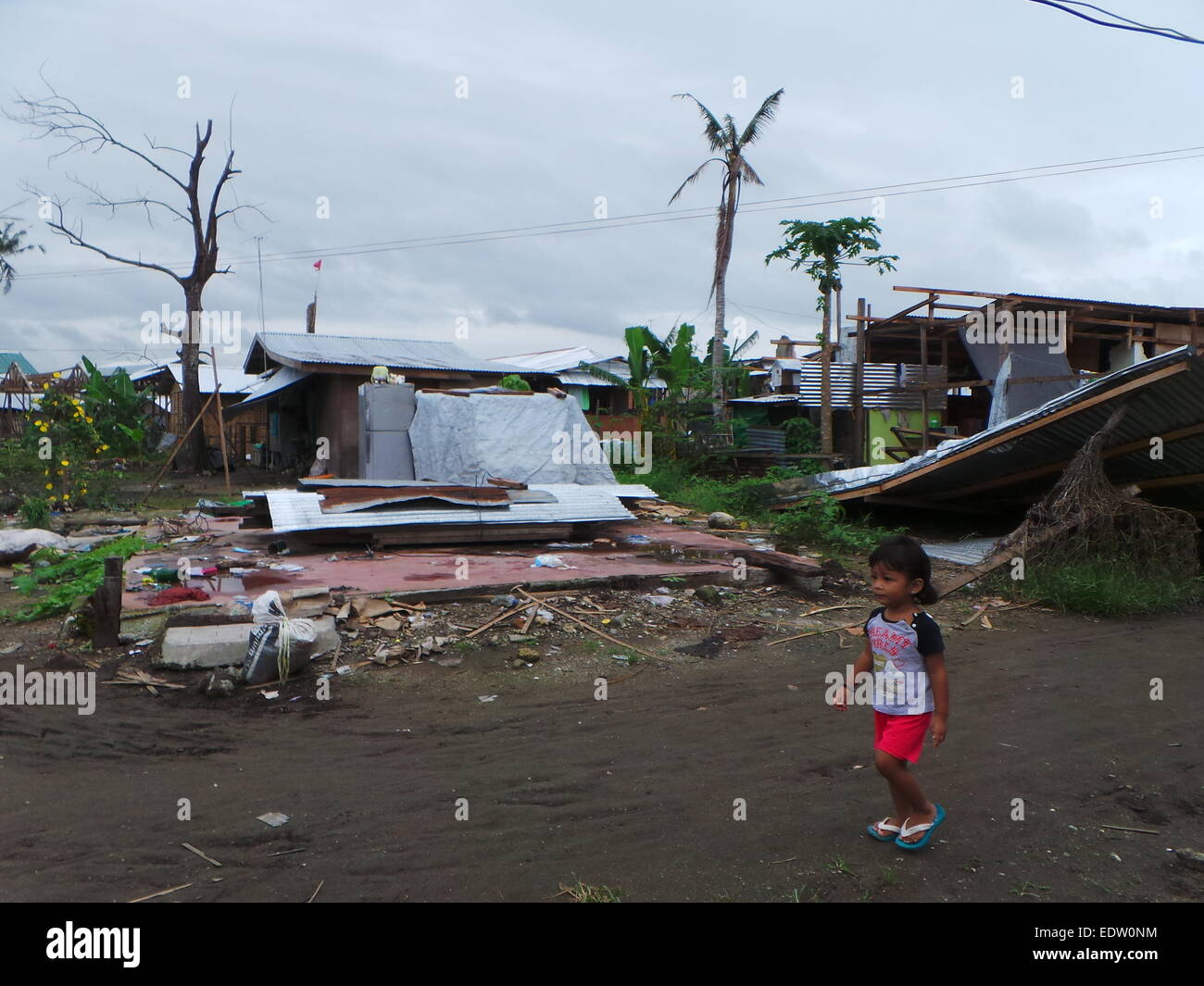 A young girl passing at a heavily damaged house by Typhoon Yolanda and ...