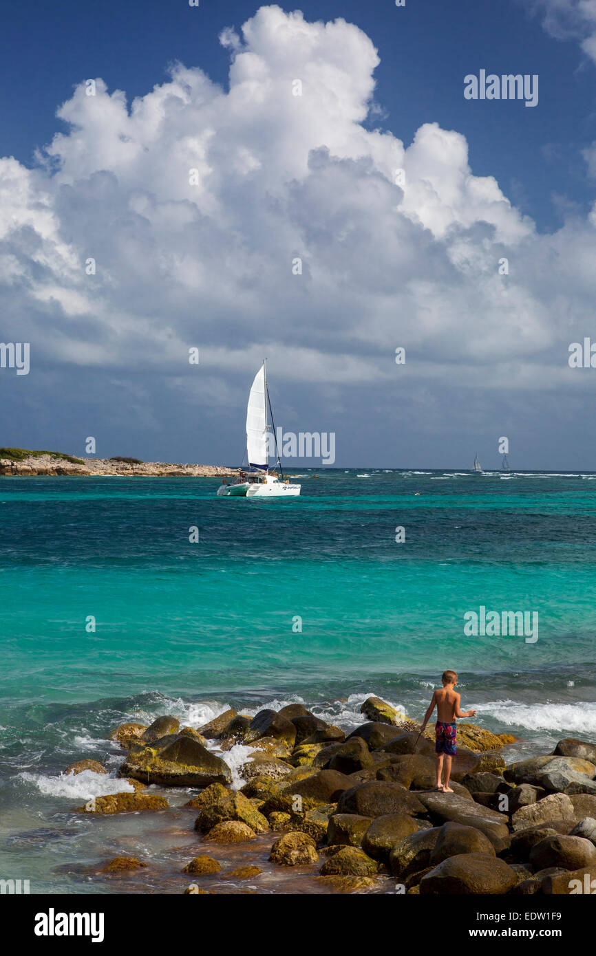 Boy watches a catamaran from Orient Beach, Saint Martin, West Indies ...
