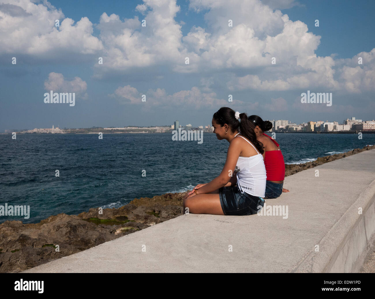 Two young Cuban women sitting on the Malecon seawall in Havana, Cuba ...