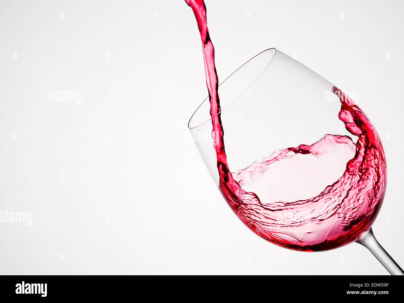Wine pouring into a glass in diagonal composition and white background ...