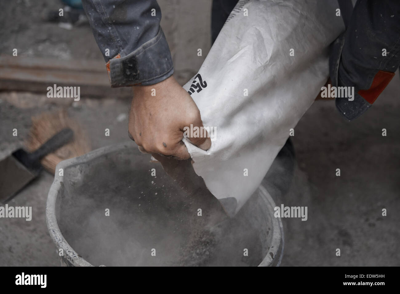 Construction worker pouring the cement to the bucket Stock Photo - Alamy