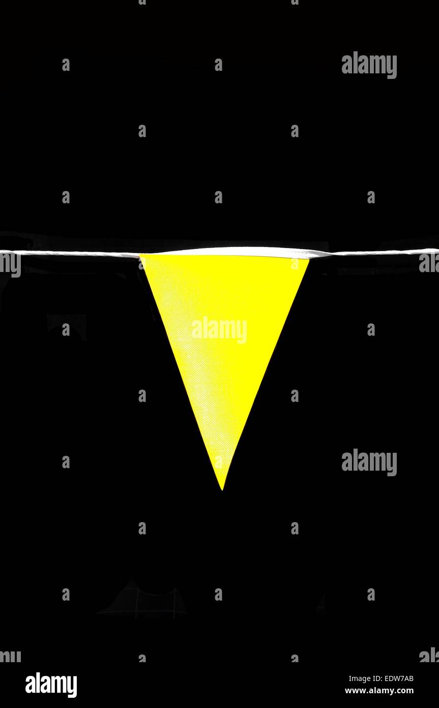 Yellow pennant flag against a black background Stock Photo - Alamy