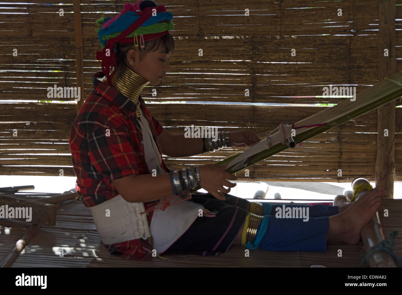 Long neck hill tribe woman weaving cloth near Chiang Rai in Northern ...