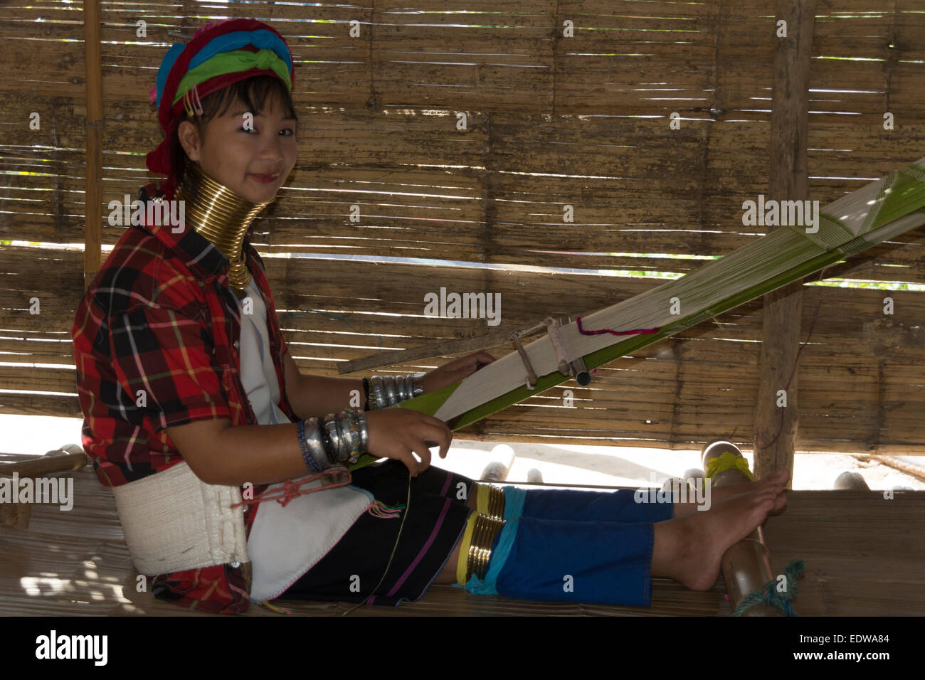 Long neck hill tribe woman weaving cloth near Chiang Rai in Northern ...