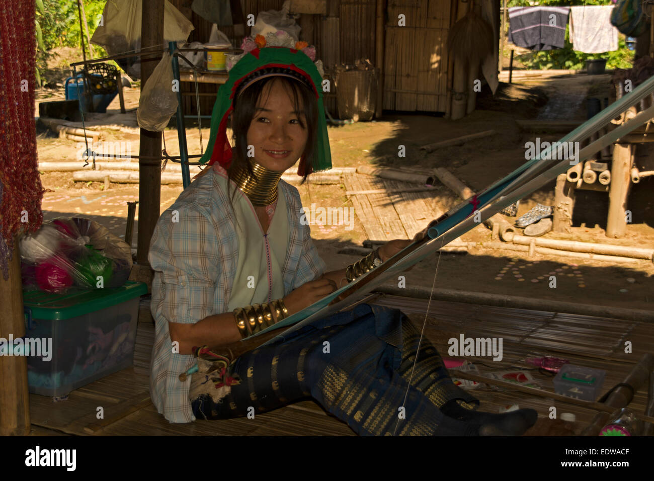 Long neck hill tribe woman weaving cloth near Chiang Rai in Northern ...