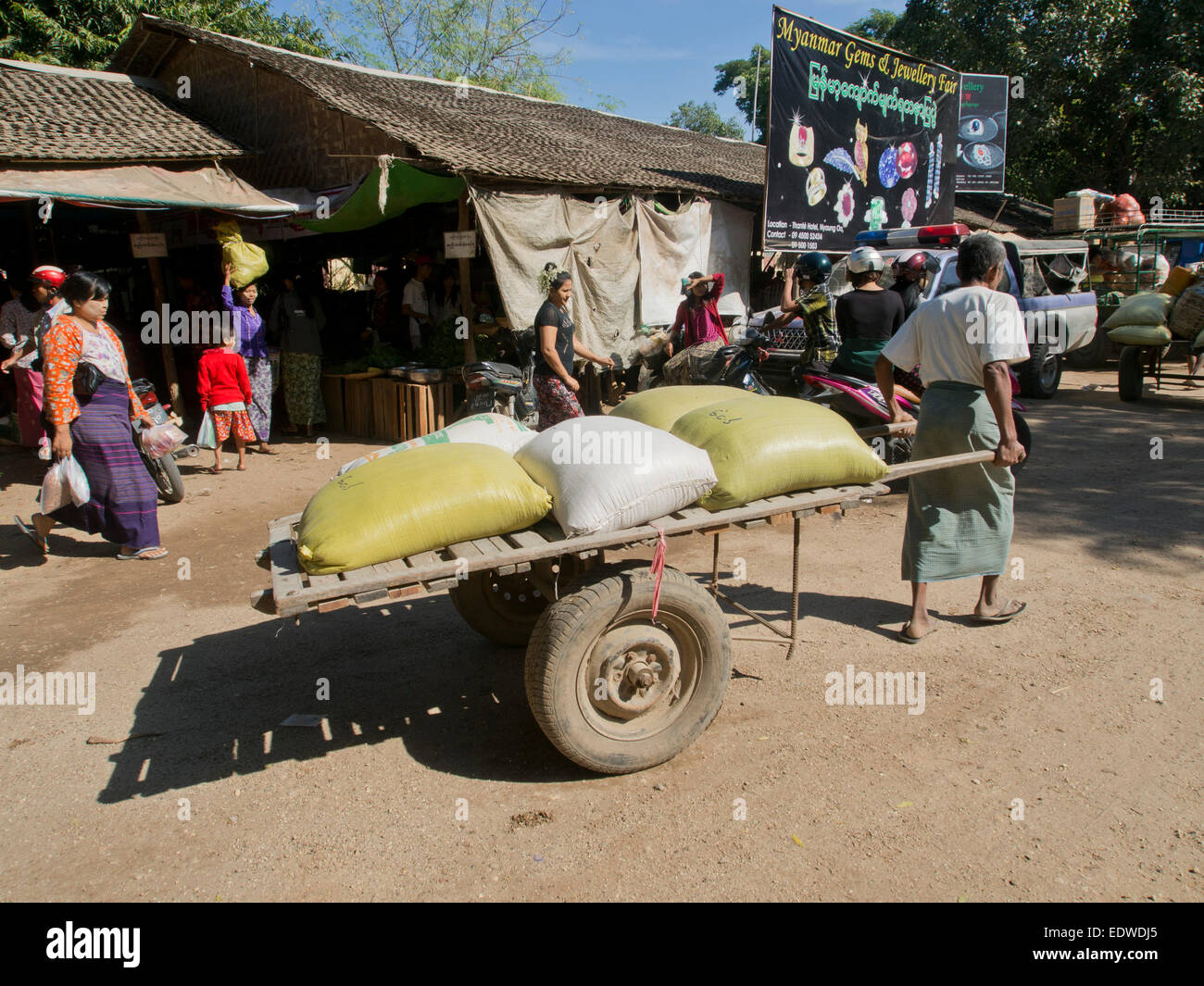 Porter carrying load on cart in a market place in a village Myanmar ...