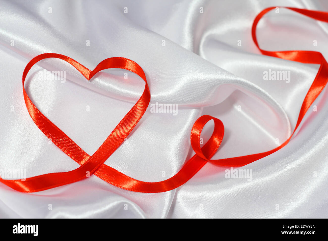 Red satin glossy ribbon heart over white silk background Stock Photo ...