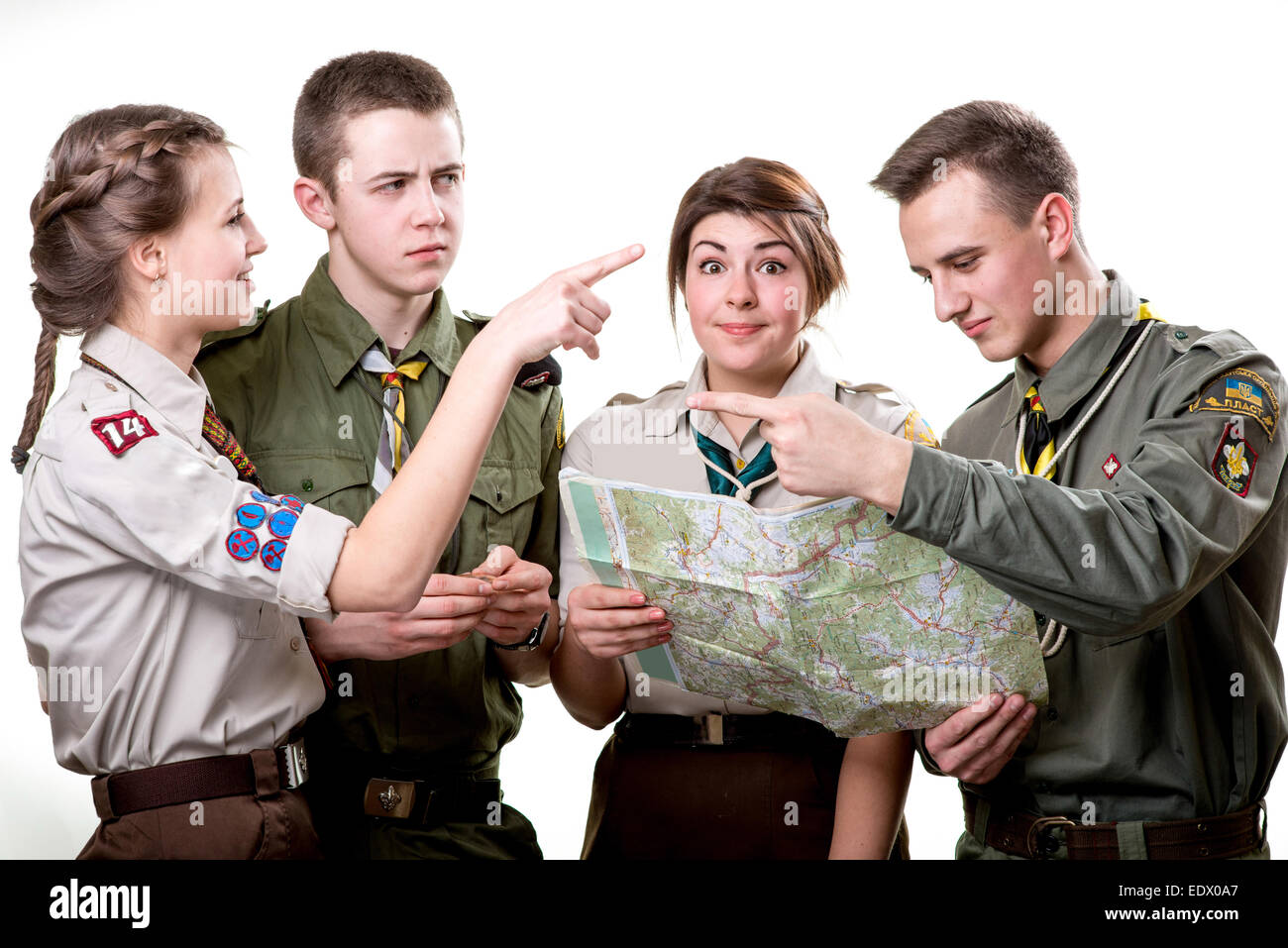 Four young scout members in uniform looking to the map and compass ...