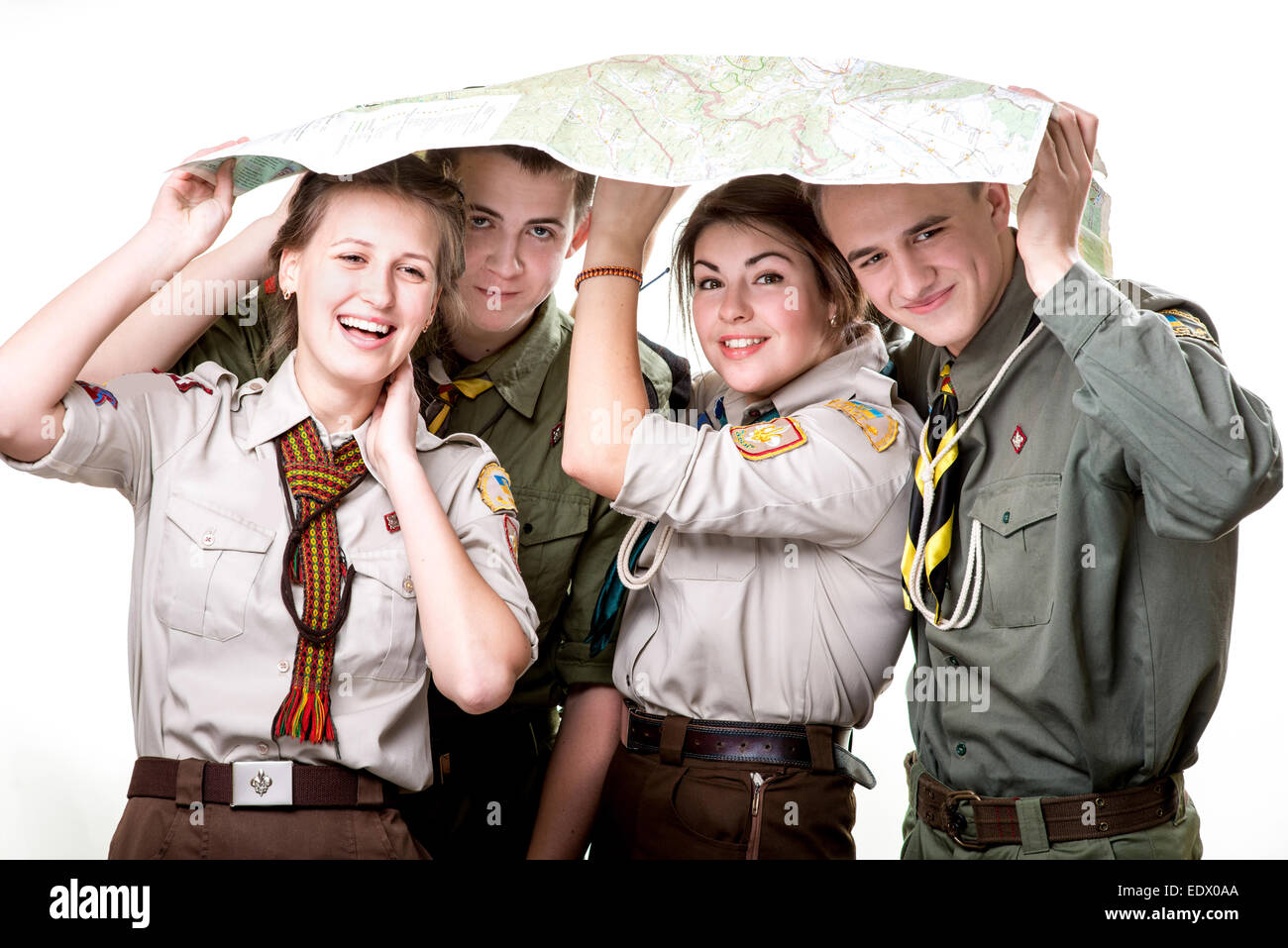 Four young scout members in uniform with map isolated on white ...
