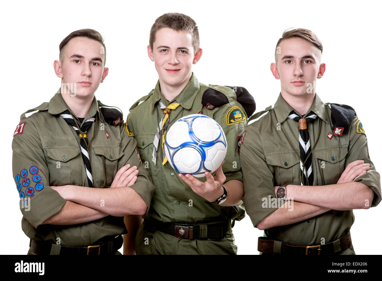 Three boy scouts standing together with the ball on white background ...