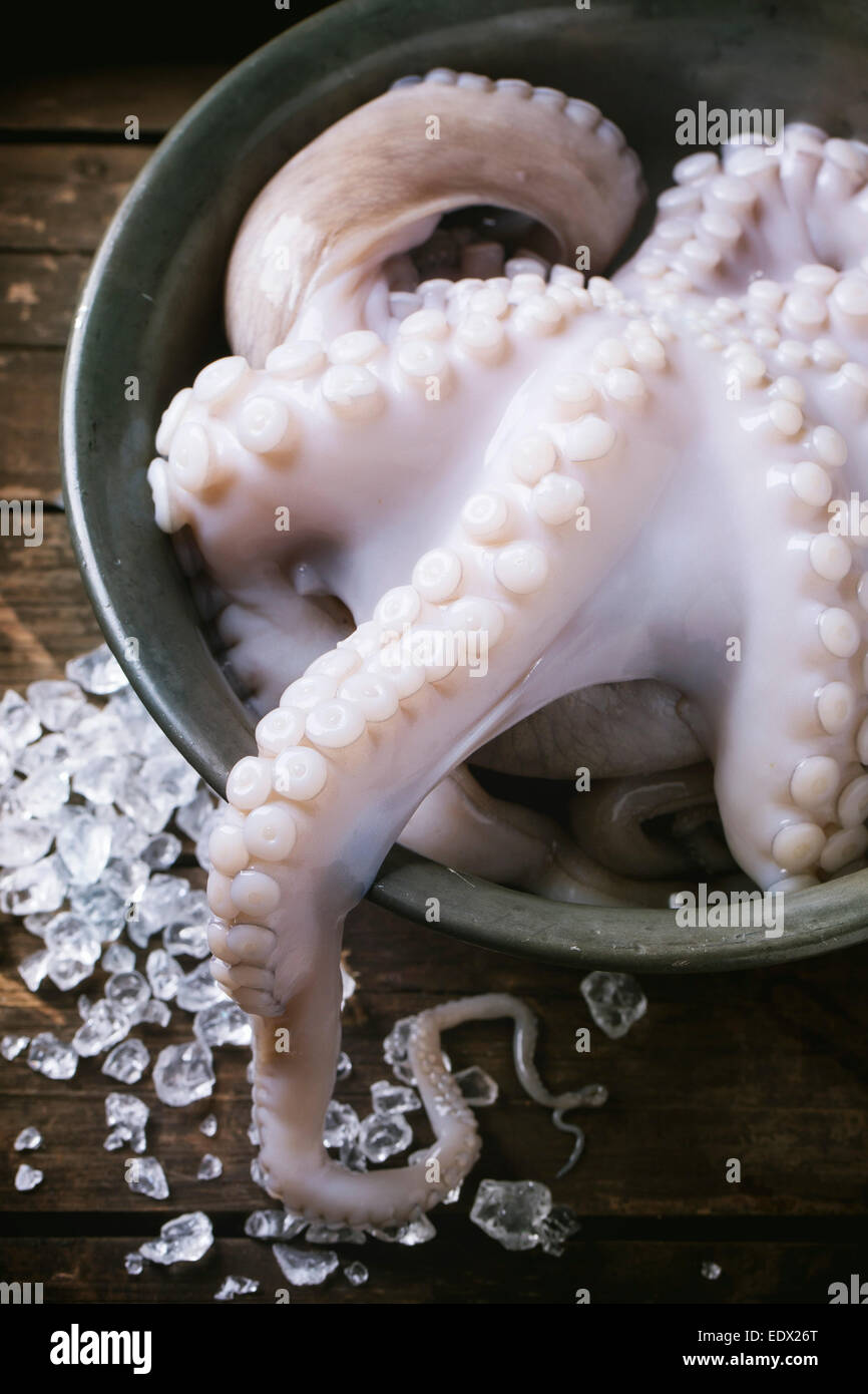 Raw octopus on ice in vintage bowl over wooden background. Top view ...