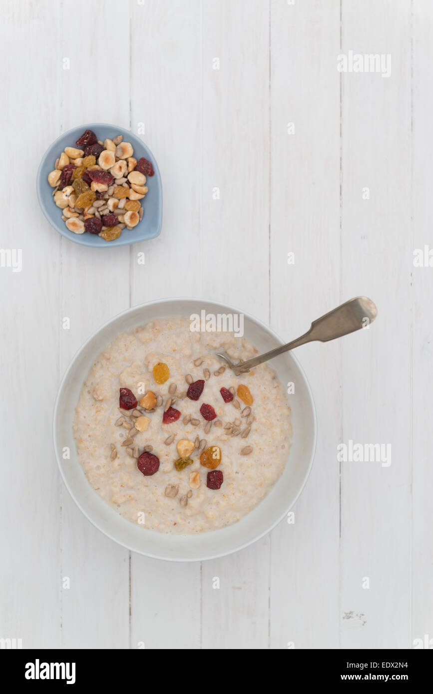 A breakfast of porridge oats srved in a white bowl on a white wooden ...