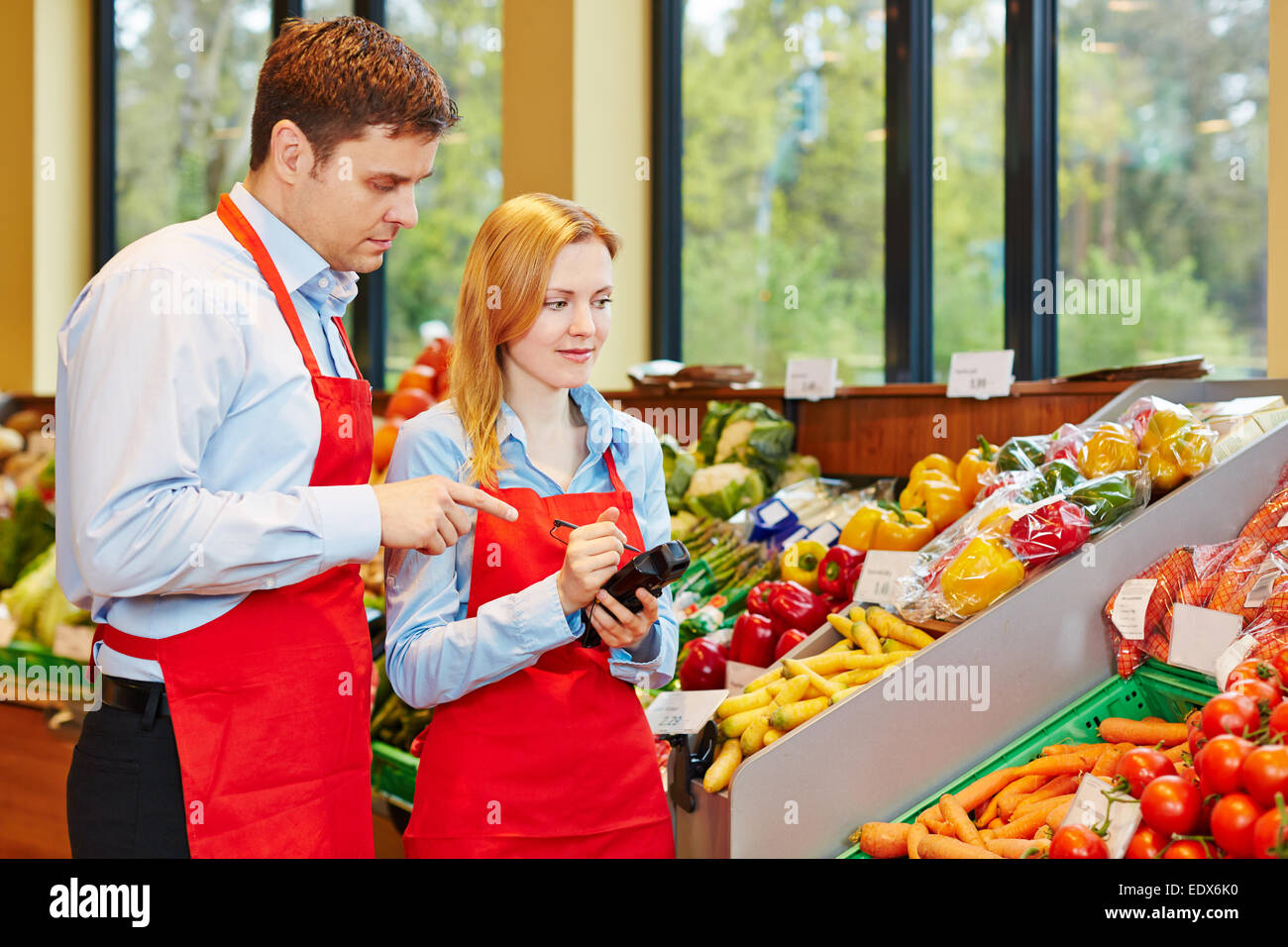 Young woman doing apprenticeship in supermarket getting help from store ...