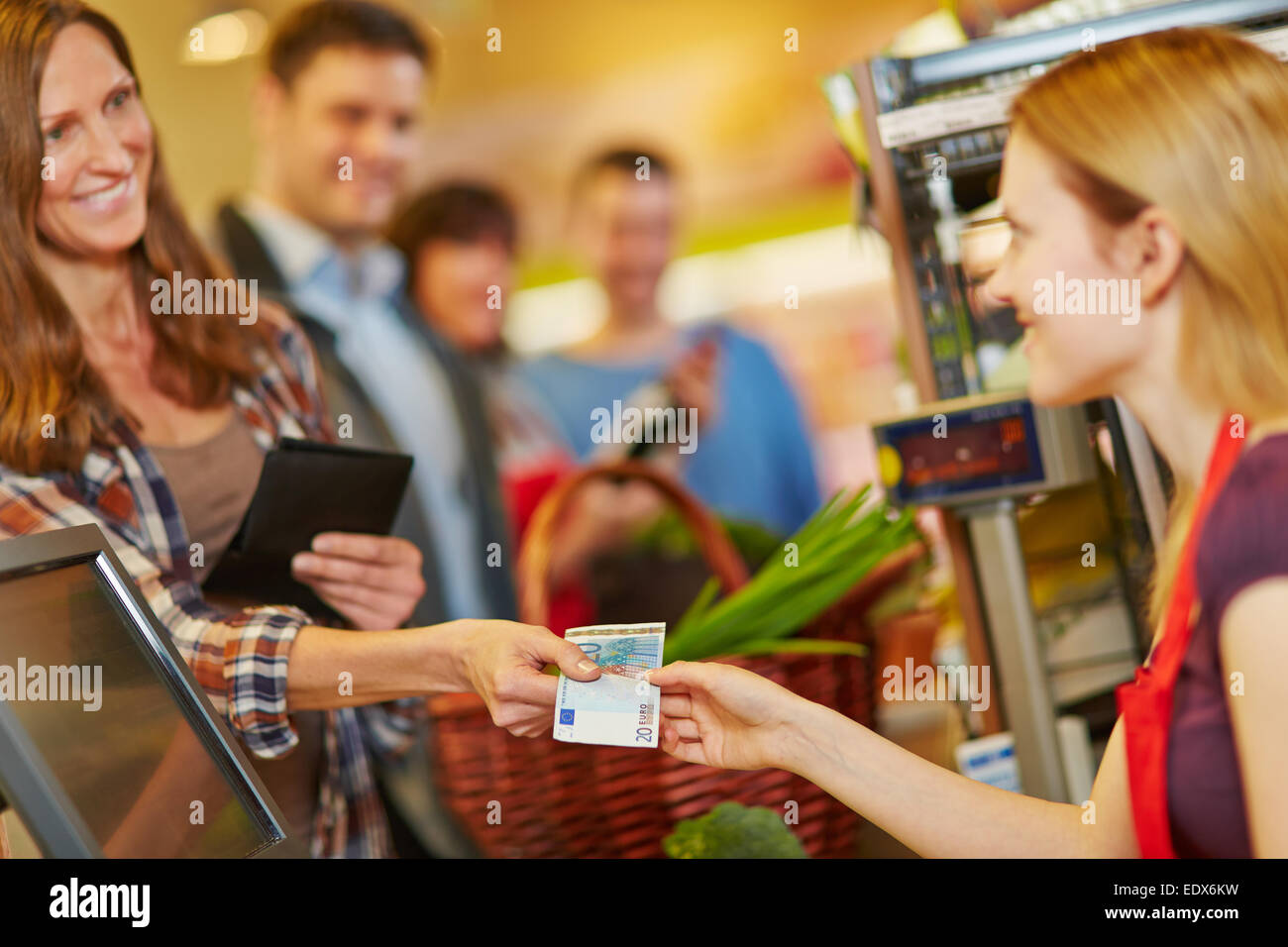 Smiling woman paying with Euro money bill at supermarket checkout Stock ...
