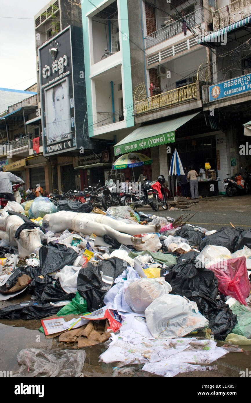 A mannequin rests in a large pile of garbage on a city street in Phnom ...